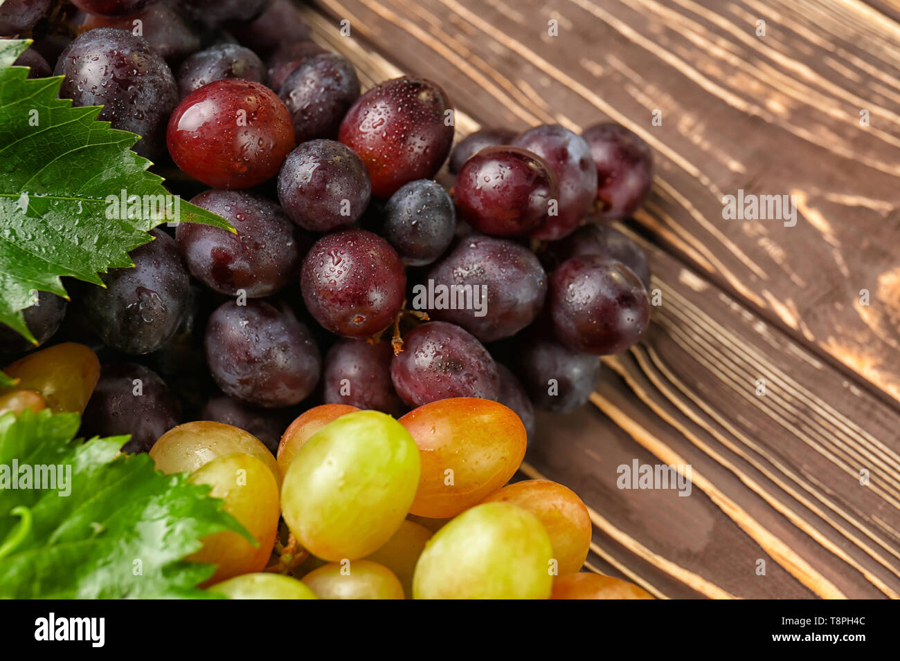 Different types of ripe sweet grapes on wooden background Stock Photo ...