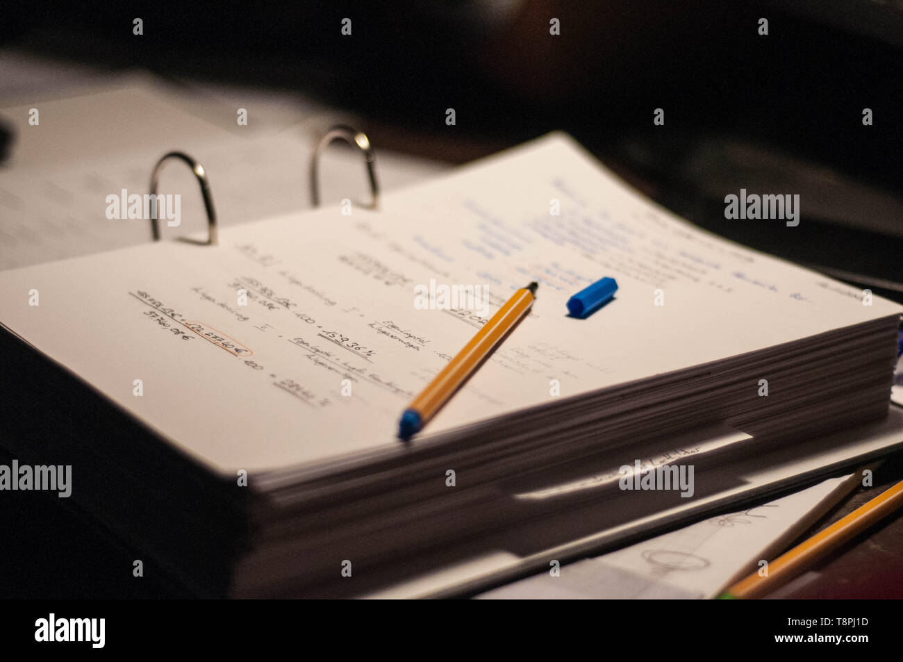 An open pen on top of an open folder with mathematical farmulas written ...