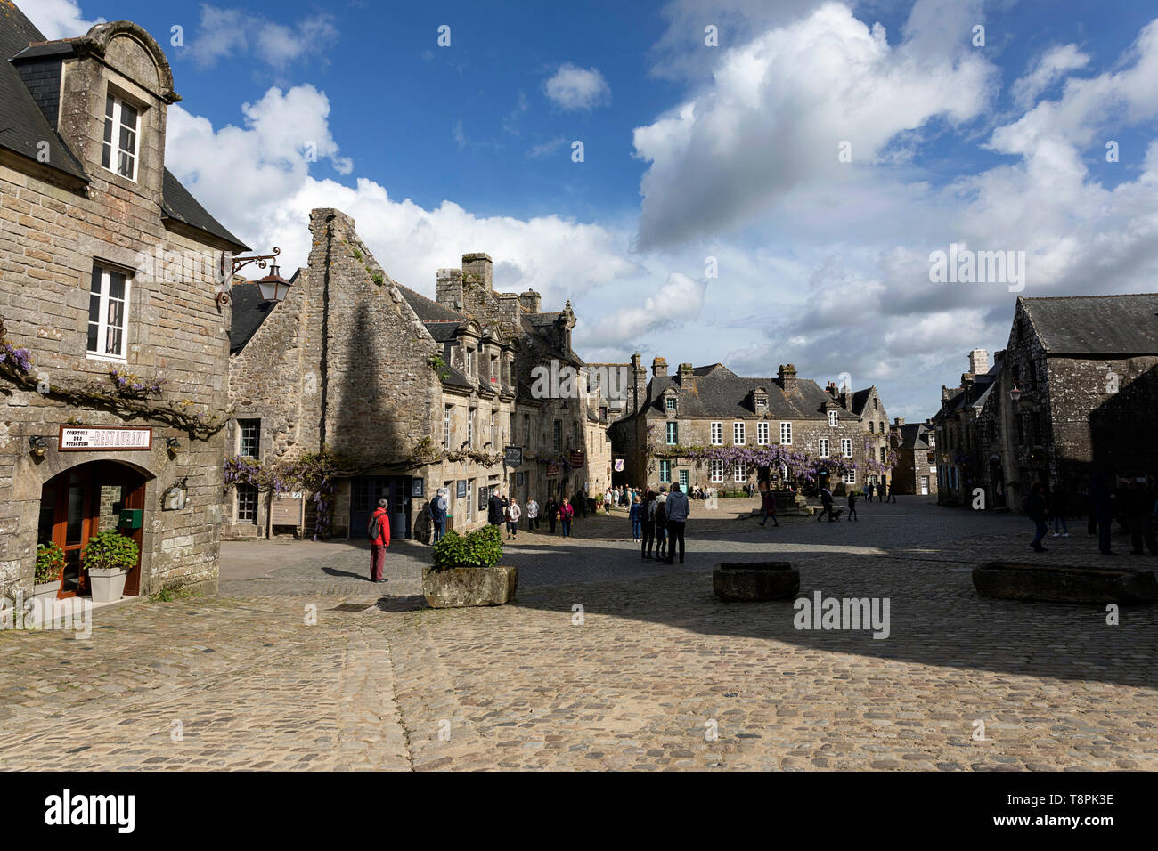 Tourists walking on streets with traditional stone houses and colorful ...