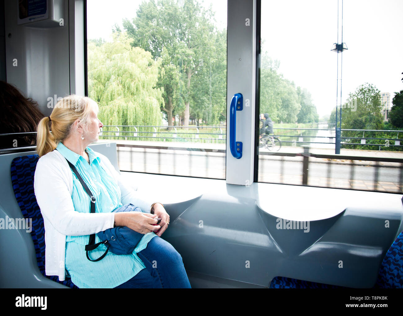 middle aged woman looking relaxed,staring out large window of train ...