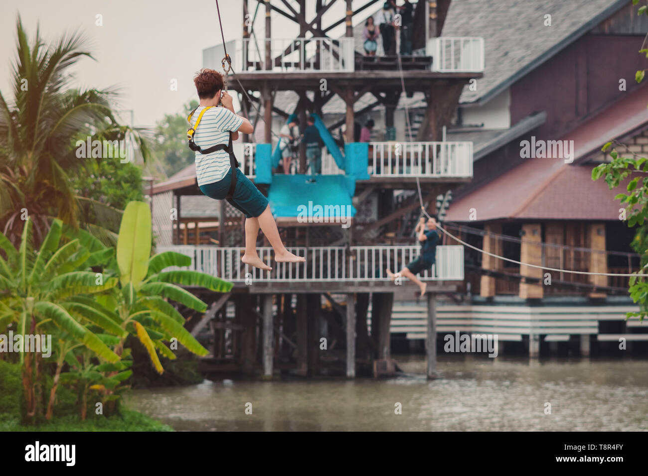 A male tourist flying on a zipline aka flying fox across the lake at ...