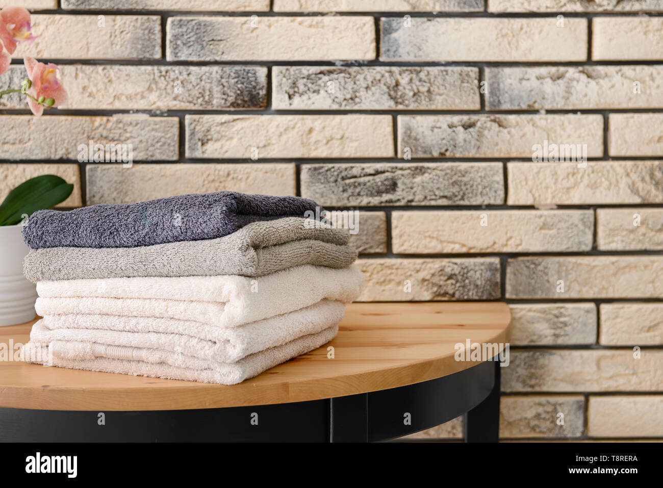 Stack of clean towels on table near brick wall Stock Photo - Alamy