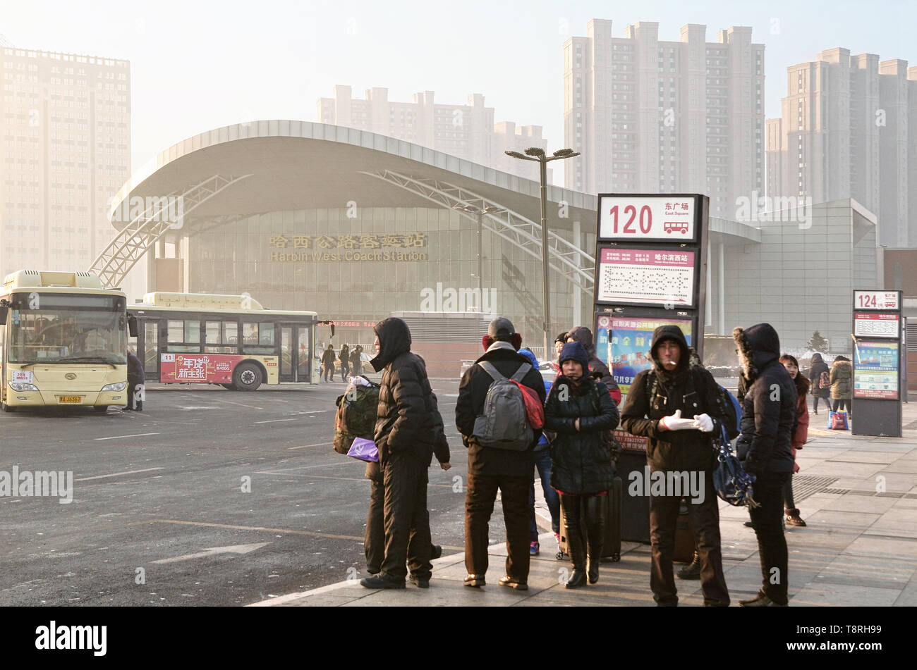 Passengers wait in queue line for public bus in parking area of Harbin ...