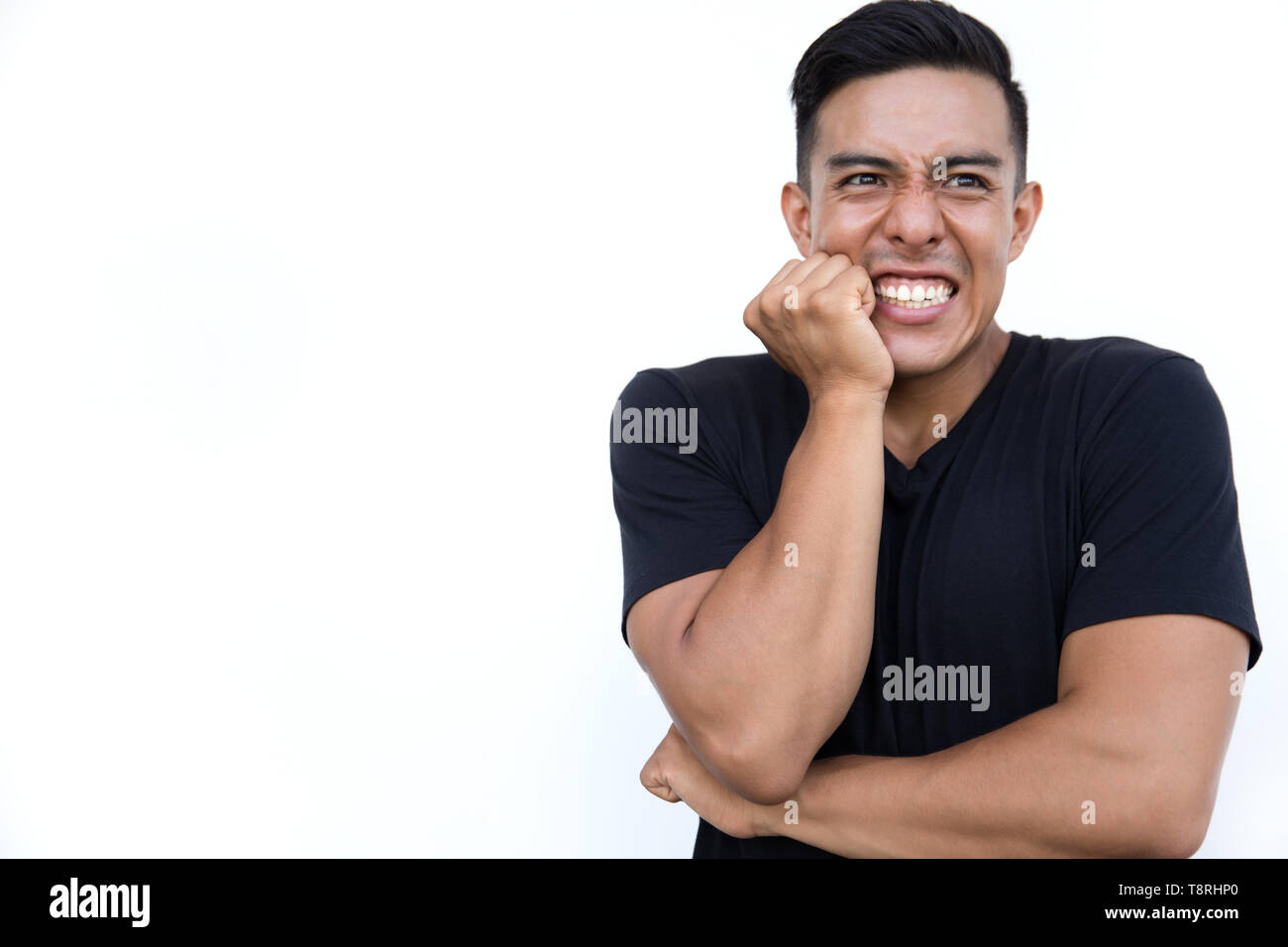 Frustrated young man holding hand on his cheek while standing on white ...