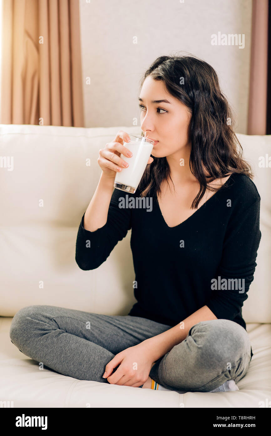 Carefree good looking brunette woman drinking milk sitting with crossed ...