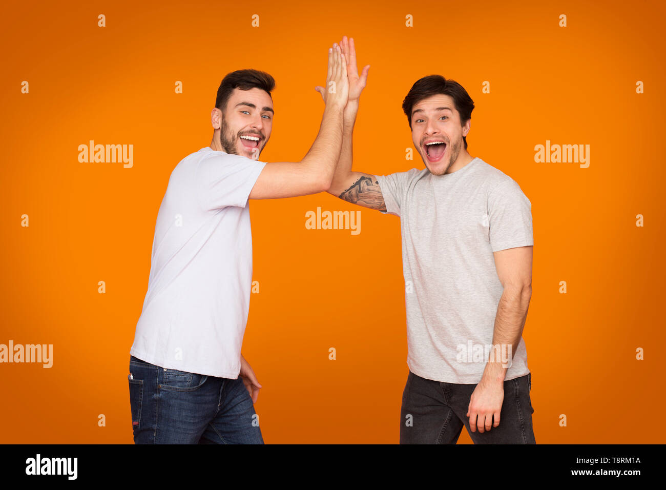 Delighted Friends Giving High Five Gesture, Orange Background Stock ...