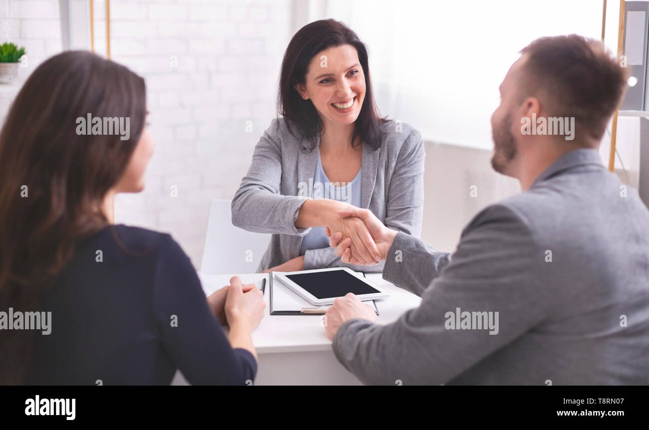 Smiling female insurance broker and young family shaking hands Stock ...