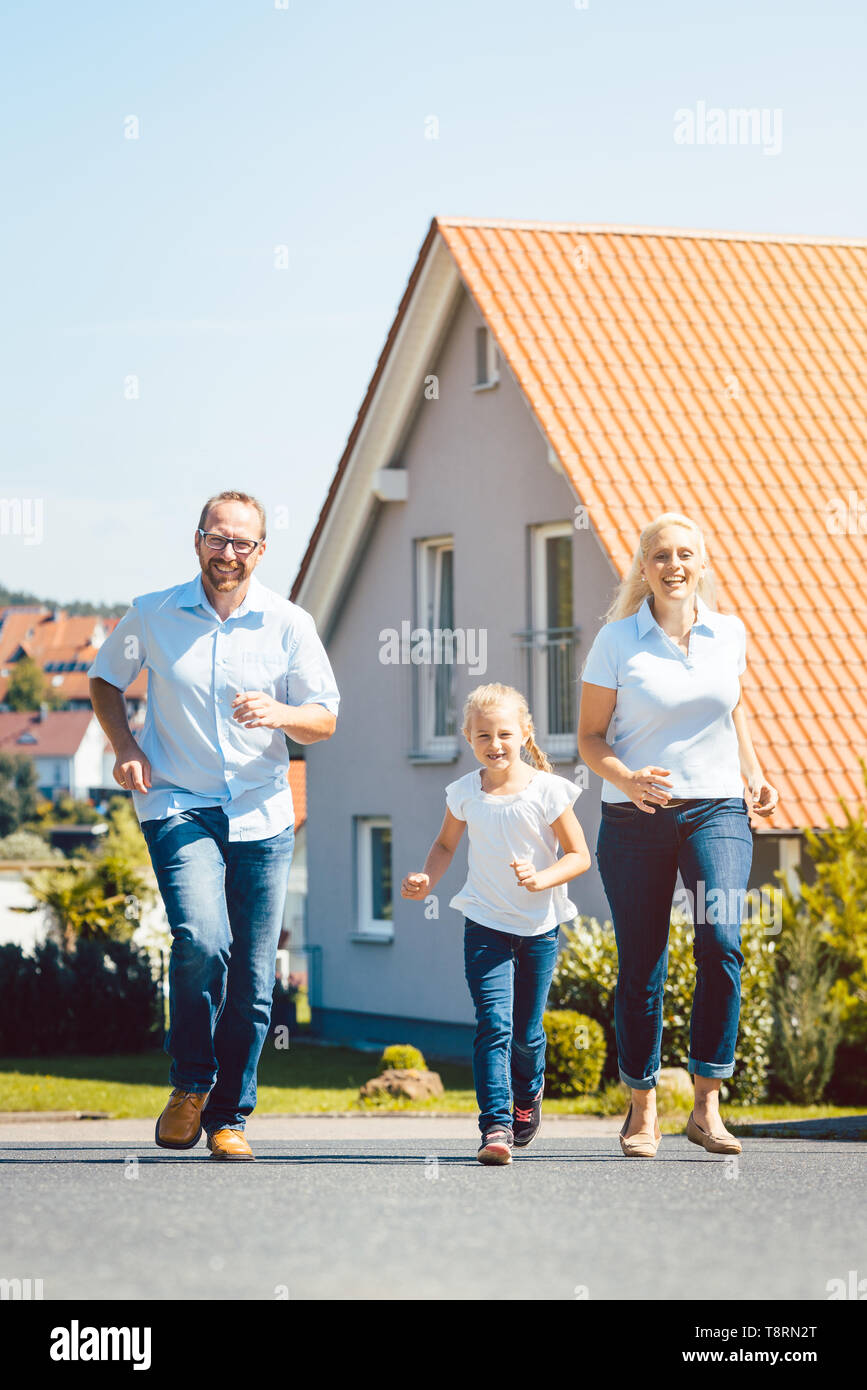 Happy family running in front of their new home in the village Stock ...