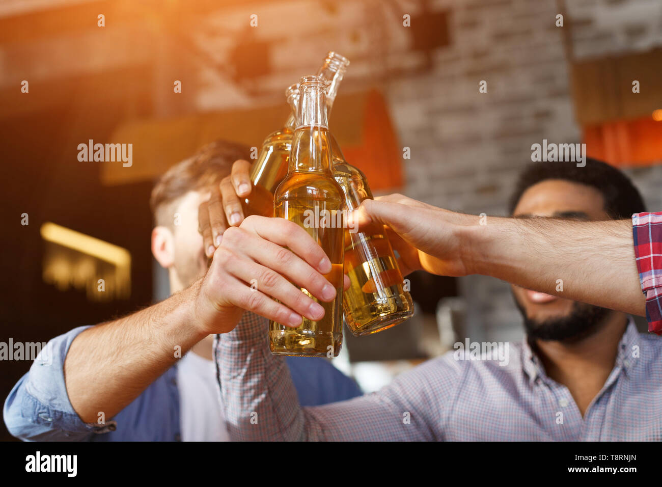 Male Friends Drinking Beer And Clinking Bottles At Bar Stock Photo - Alamy