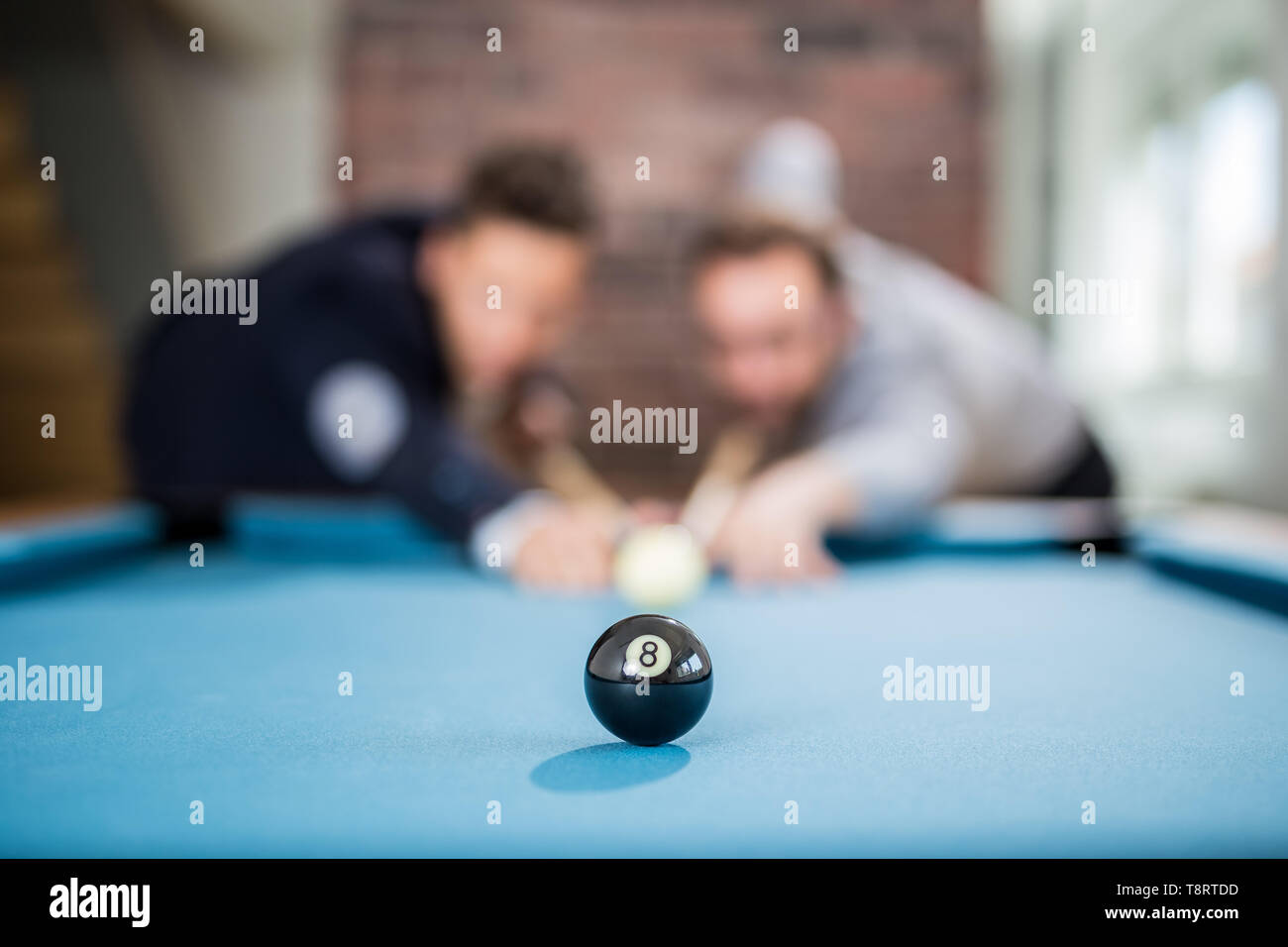 Two fashionable men friends aiming black pool ball Stock Photo - Alamy