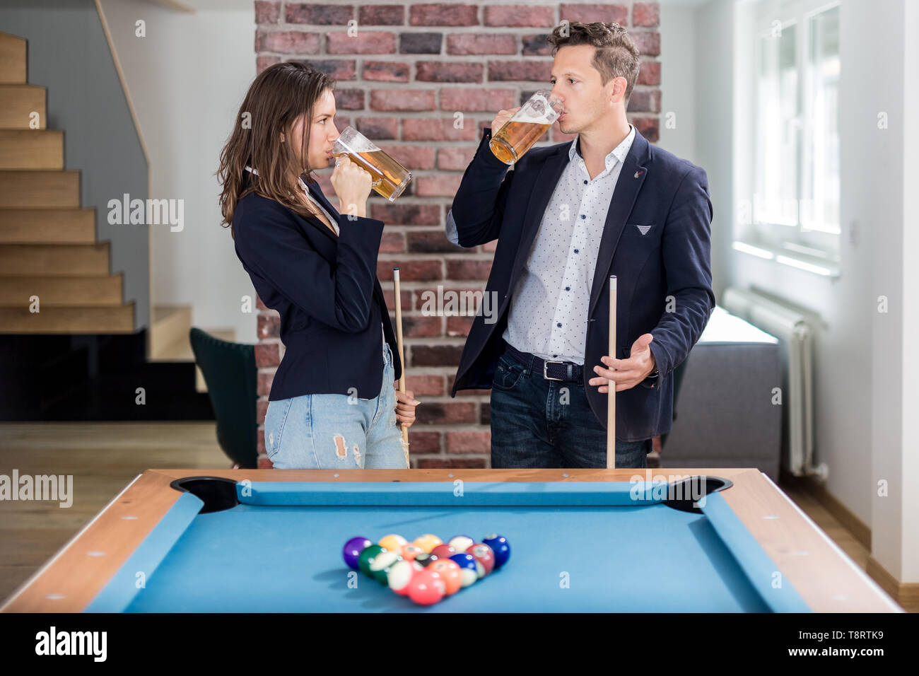 Couple drinking beer next to billiard pool table Stock Photo - Alamy
