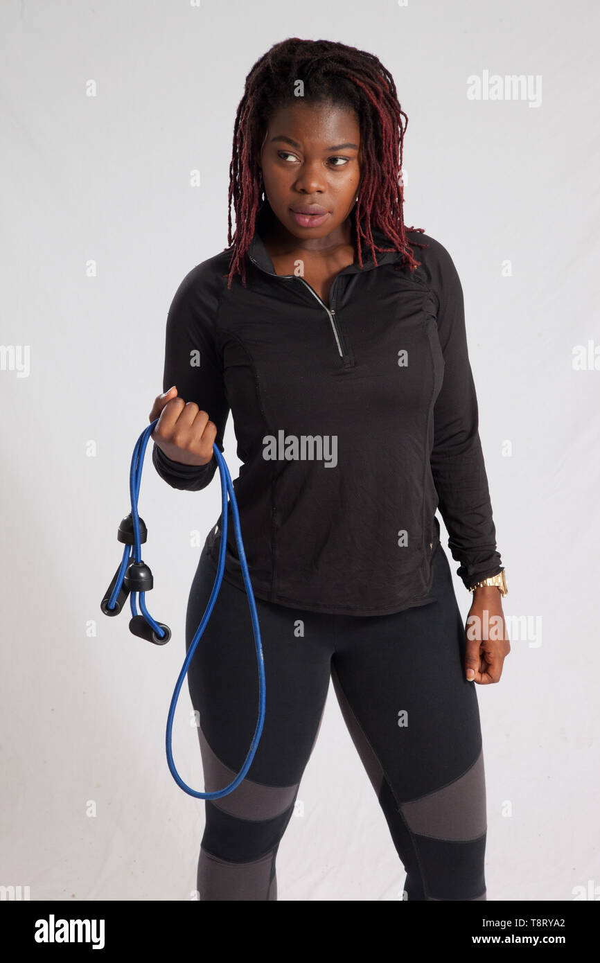 Lovely Black woman in exercise outfit with a pull rope Stock Photo - Alamy