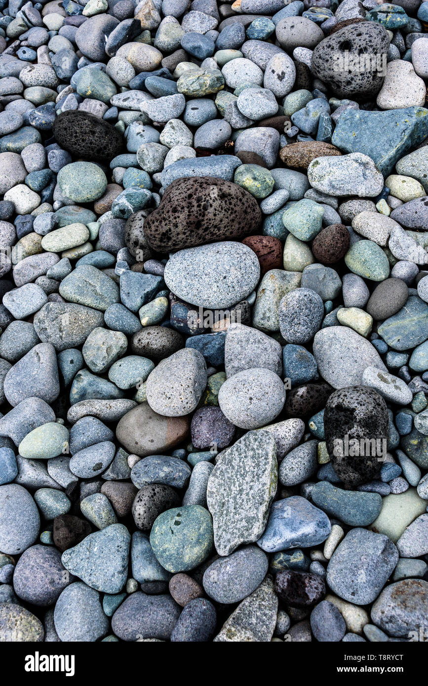 Sea tumbled round rocks on a beach with a few volcanic rocks mixed in ...