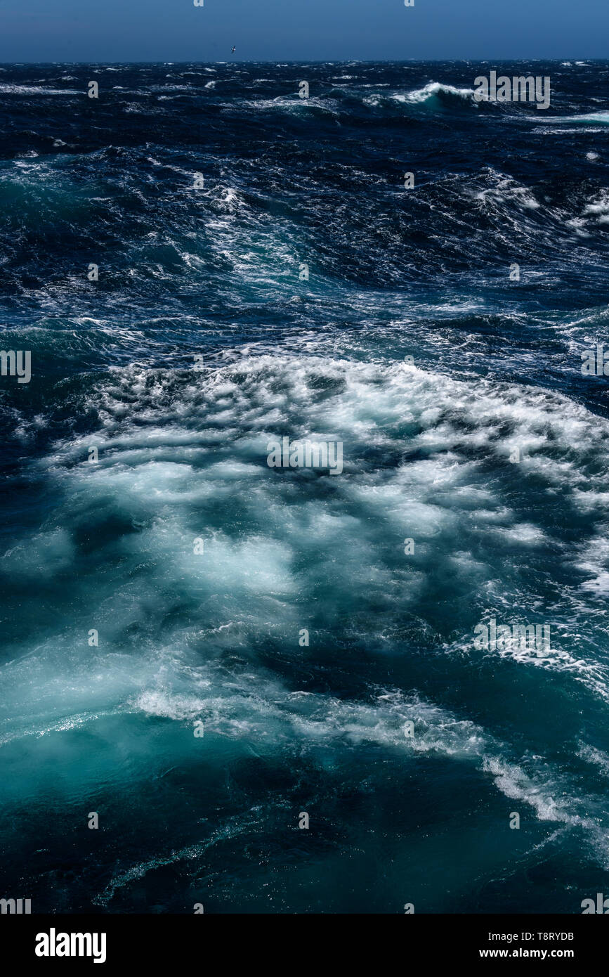 Turquoise and blue ocean water with a trail of bubbles and waves as a ...
