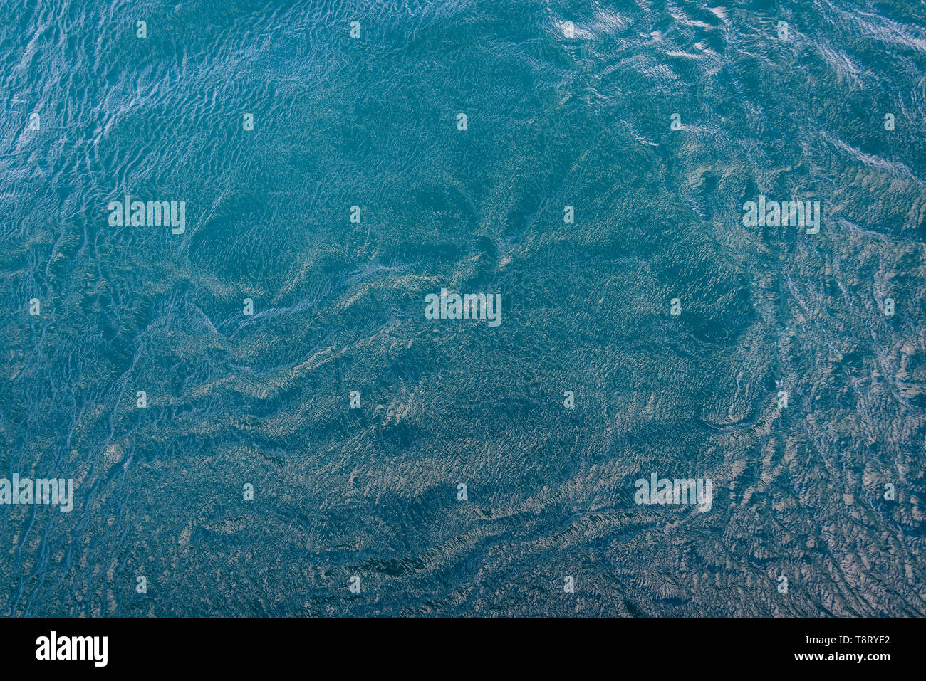 Turquoise ocean water with pattern and texture is small waves as a ...