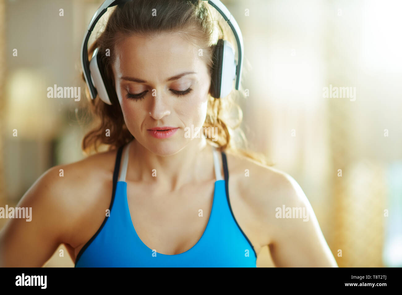 active woman in sport clothes listening to the music with headphones in ...