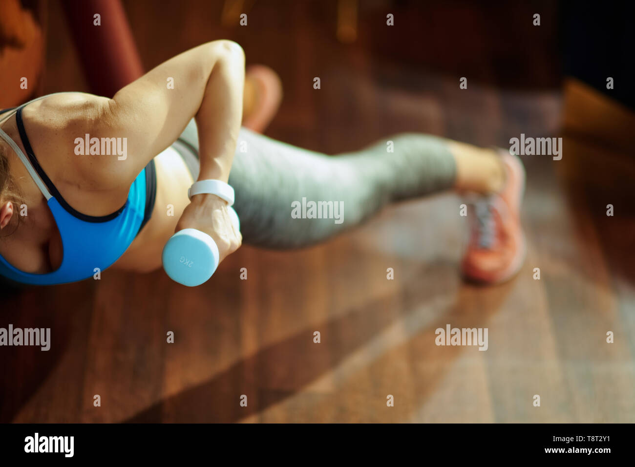 Closeup on young woman in sport clothes with blue dumbbell workout in ...
