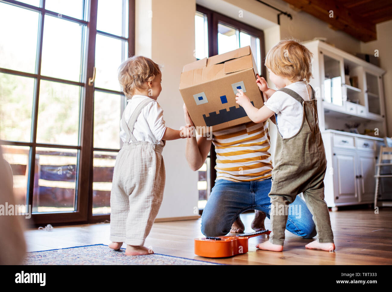 Two happy toddler children with a father and carboard monster playing ...