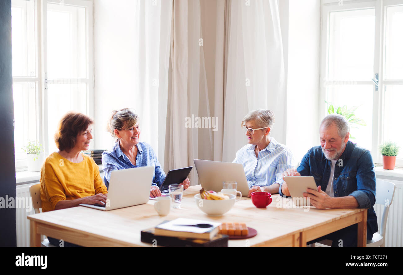 Group of senior people using laptops and tablets in community center ...