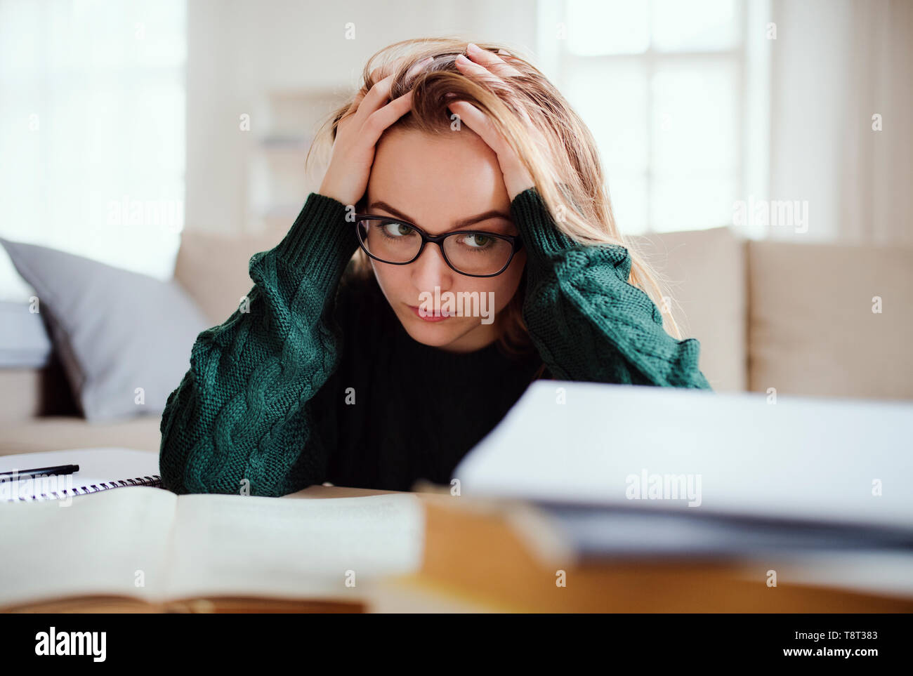 A young unhappy and sad college female student sitting at the table at ...
