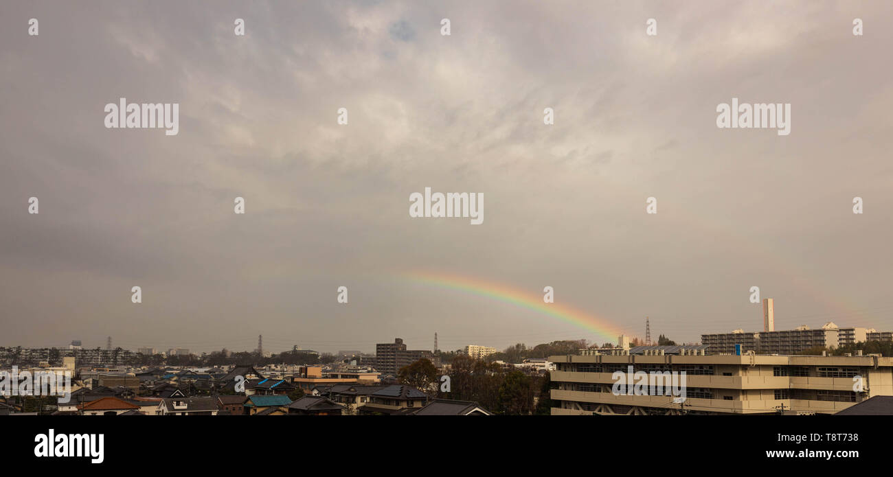 Rainbow with faint double curves through sky over urban landscape Stock ...