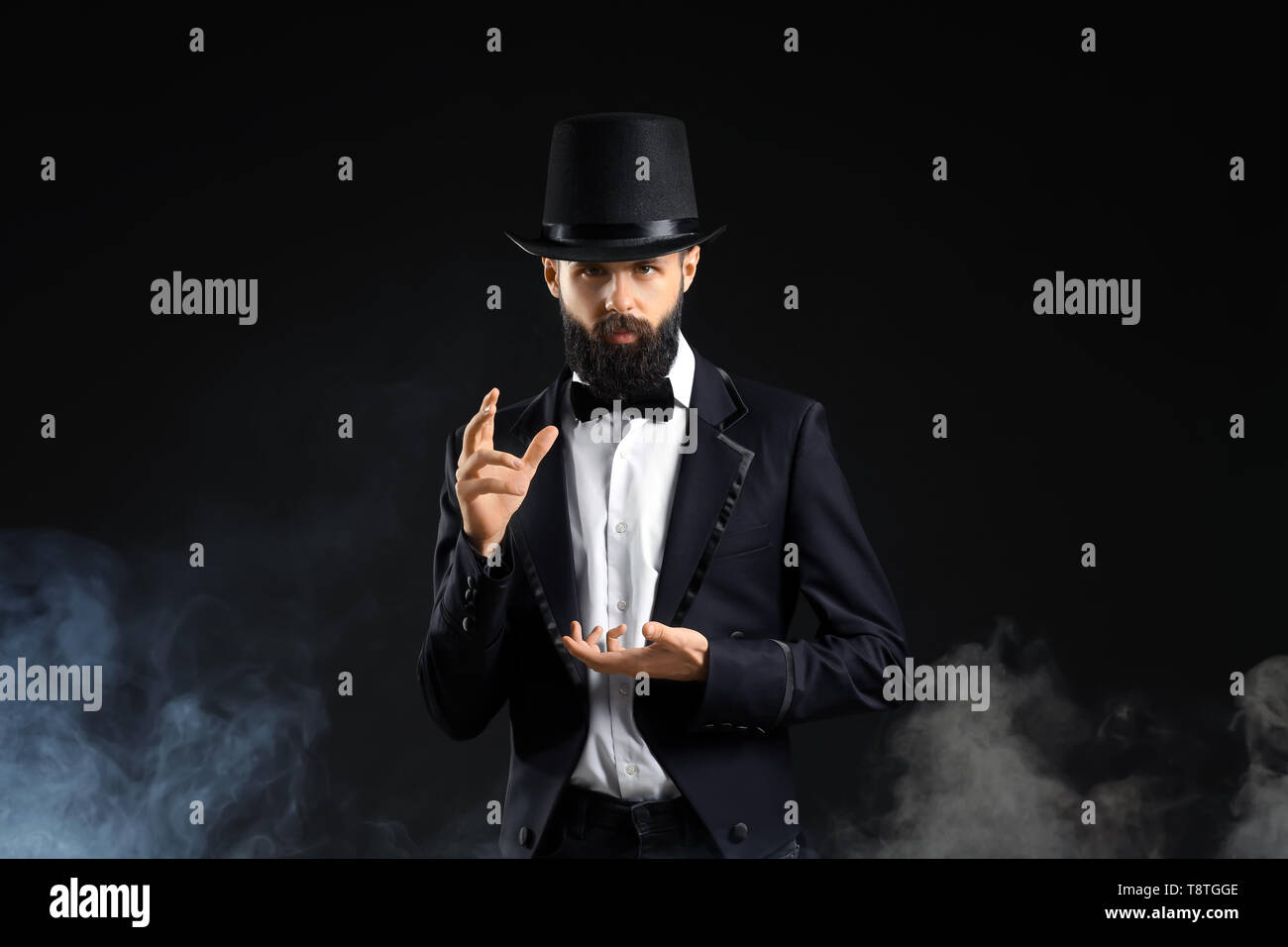 Magician showing tricks in smoke on dark background Stock Photo - Alamy