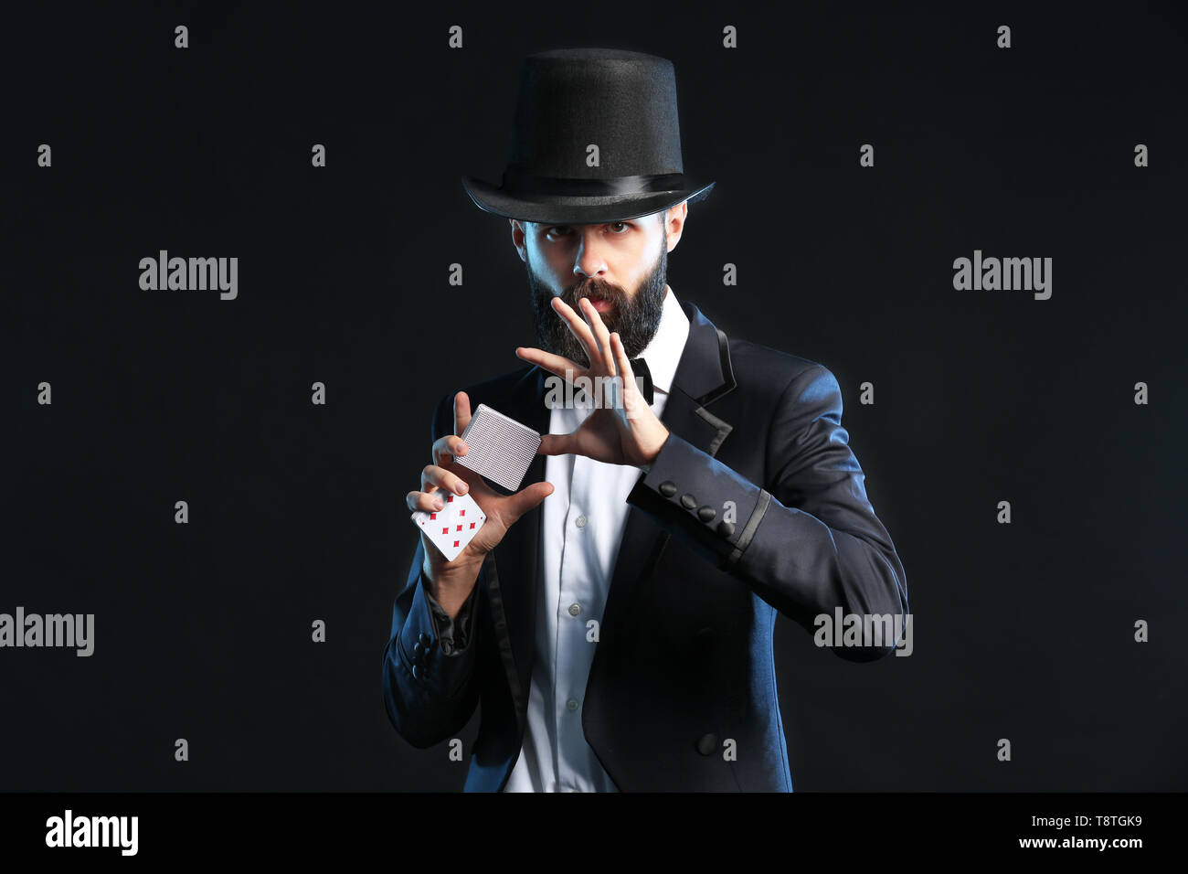 Magician showing tricks with cards on dark background Stock Photo - Alamy