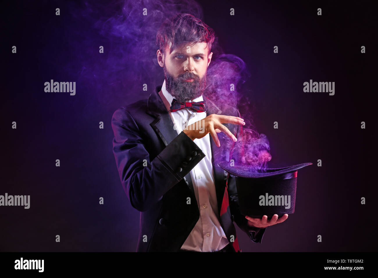 Magician showing tricks with hat on dark background Stock Photo - Alamy