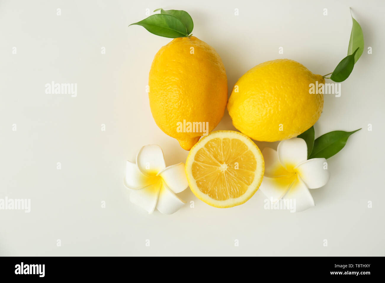 Ripe juicy lemons and exotic flowers on white background, top view ...