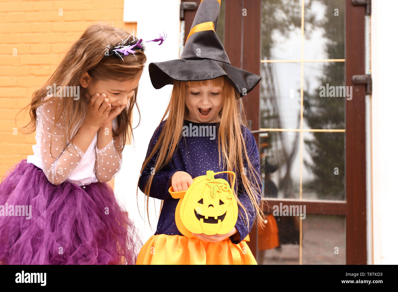 Cute little girls in Halloween costumes looking inside their bag ...