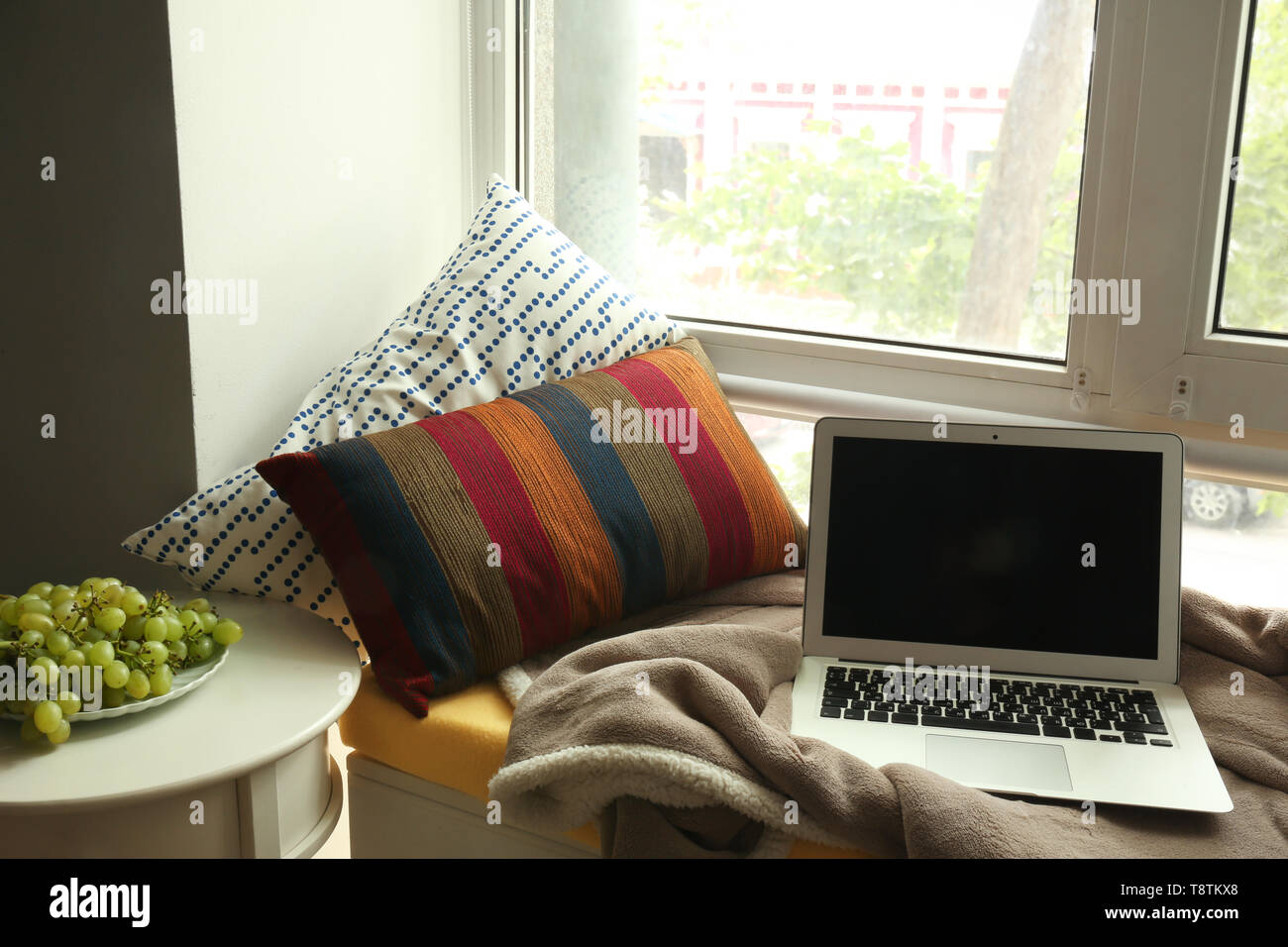 Cozy place for rest with soft pillows and laptop near window Stock ...