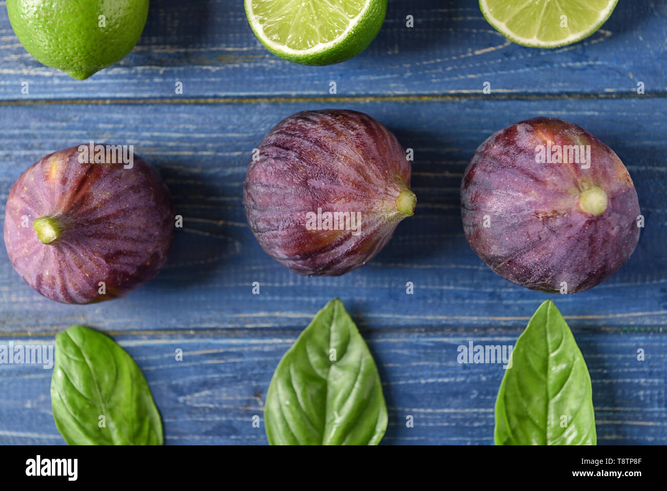 Composition with ripe figs, lime and basil on color wooden background ...