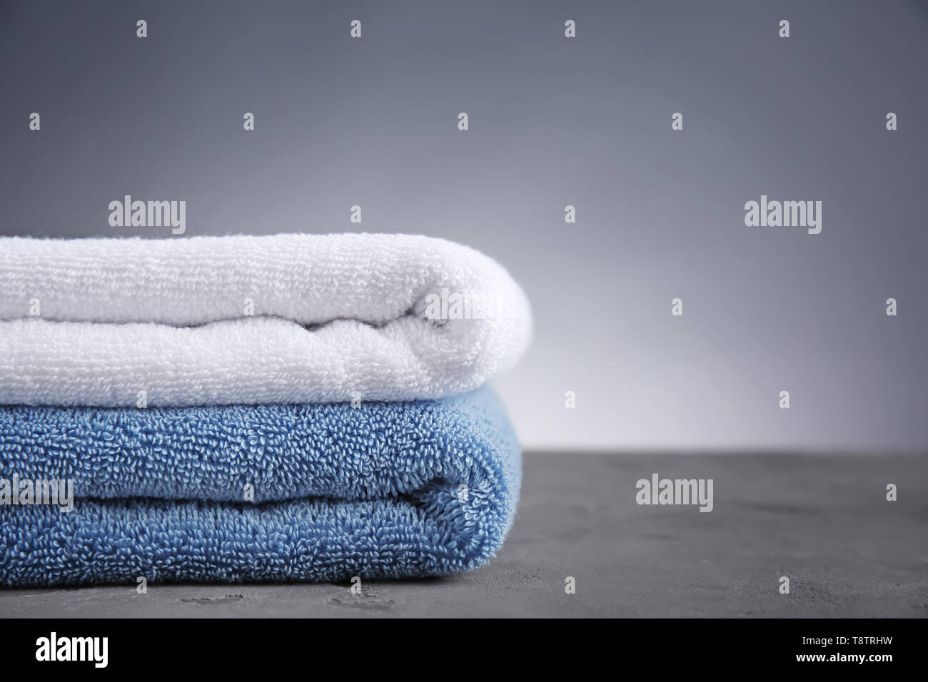 Stack of clean soft towels on table against grey background Stock Photo ...