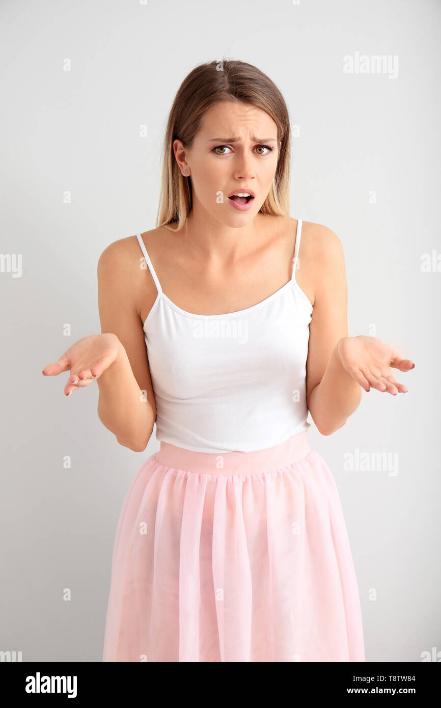 Confused young woman on white background Stock Photo - Alamy
