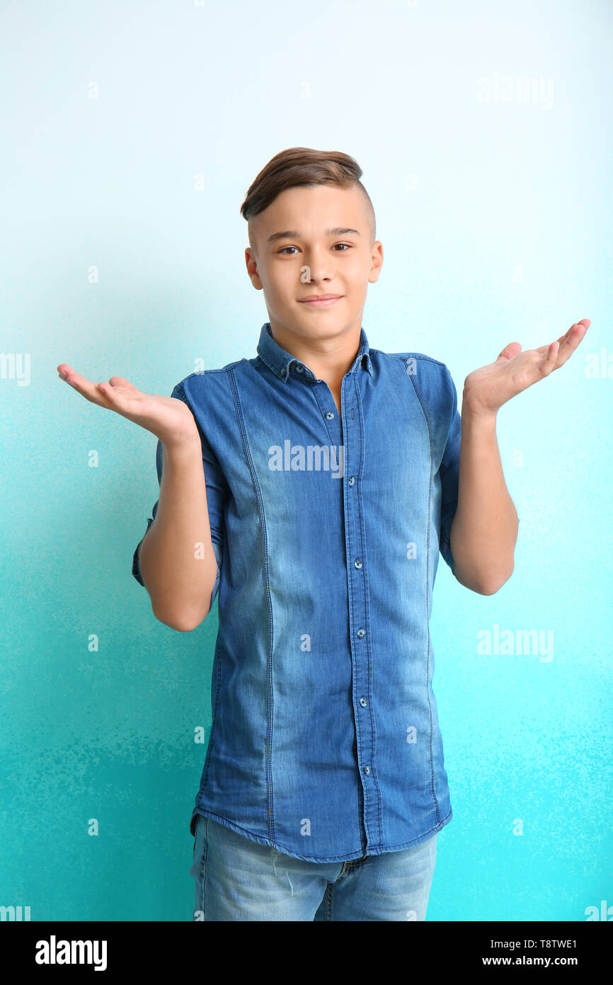 Confused teenage boy on color background Stock Photo - Alamy