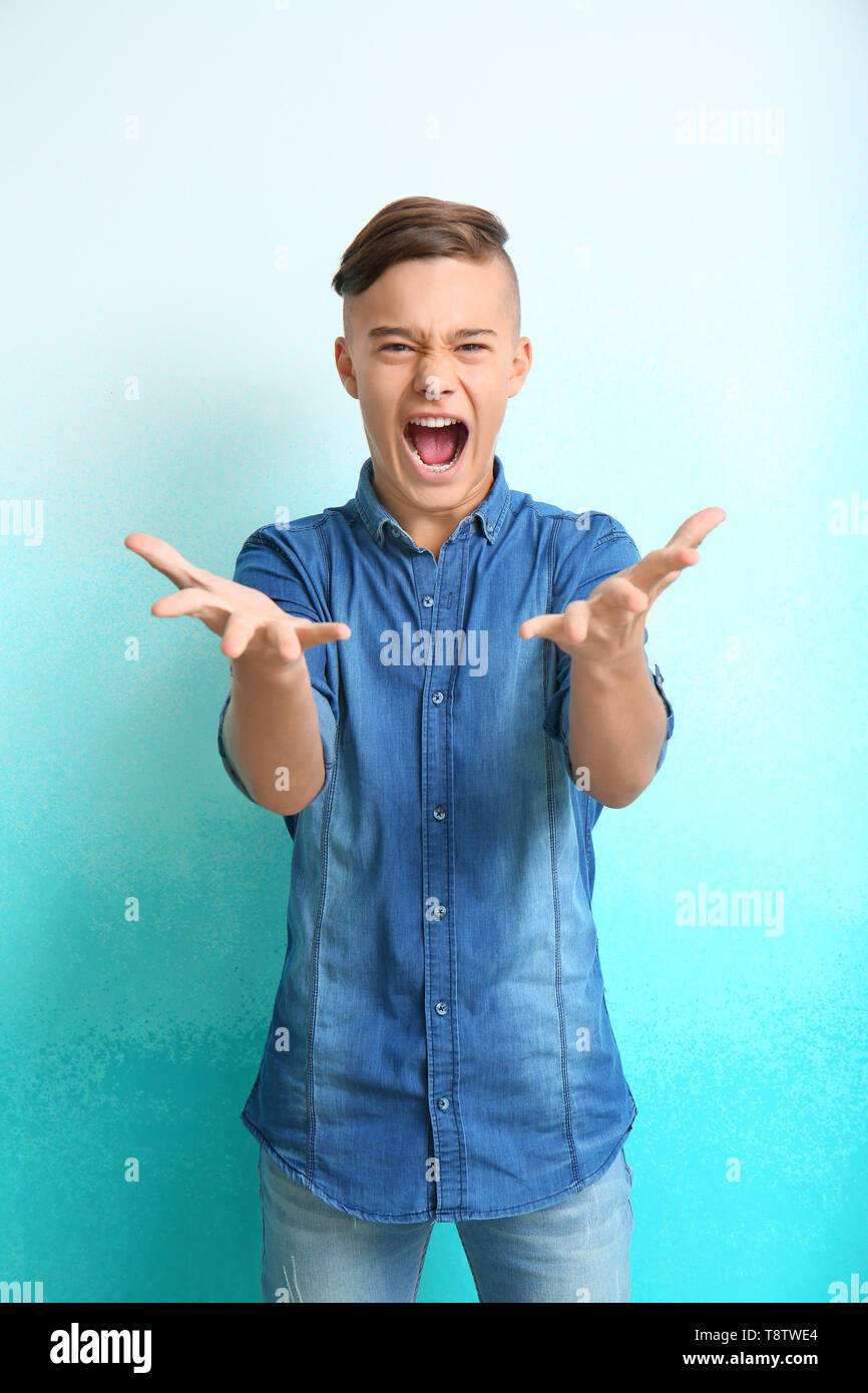 Irritated teenage boy on color background Stock Photo - Alamy