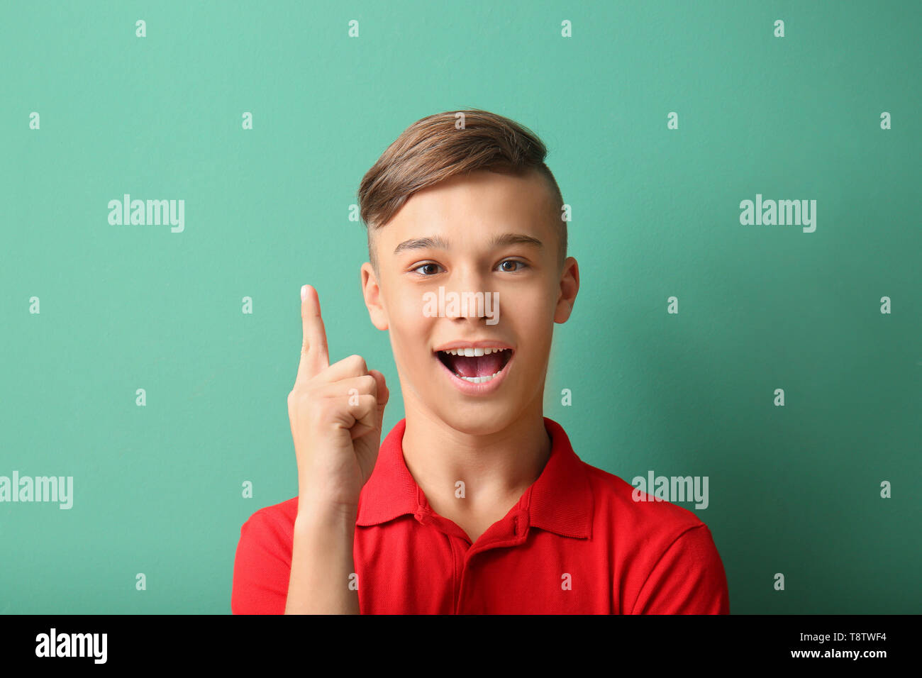 Teenage boy with raised index finger on color background Stock Photo ...