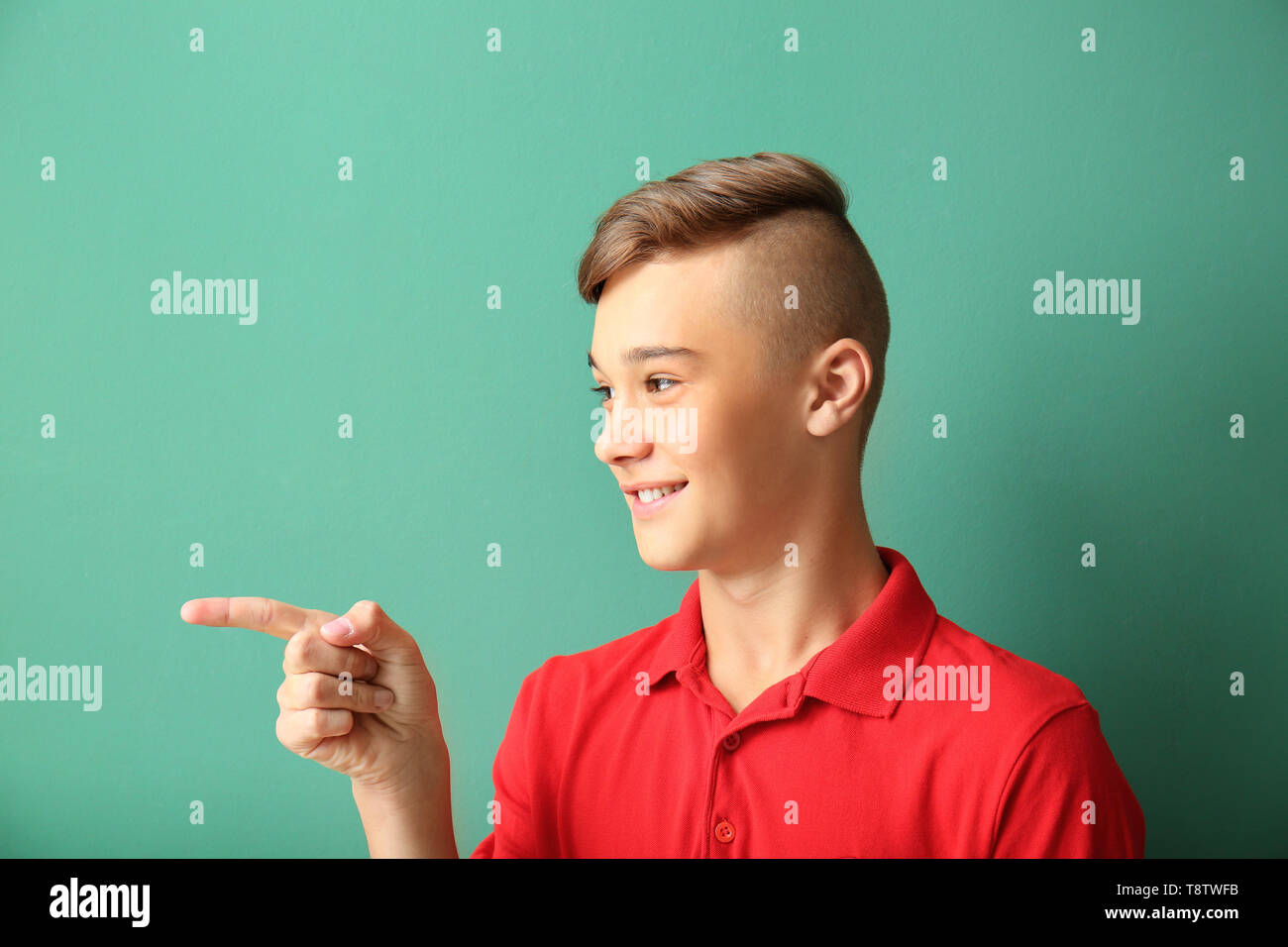Teenage boy pointing at something on color background Stock Photo - Alamy