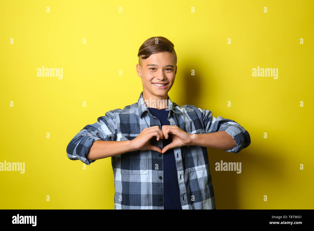 Teenage boy making heart with his hands on color background Stock Photo ...