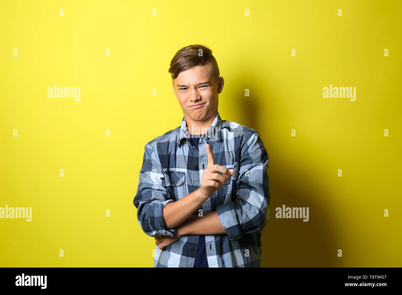 Emotional teenage boy waggling finger at viewer on color background ...