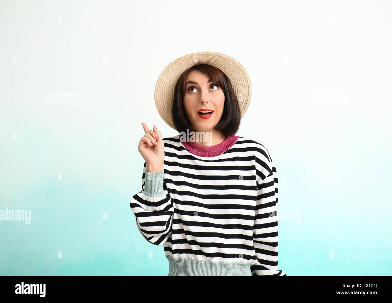 Portrait of beautiful woman with raised index finger on color ...