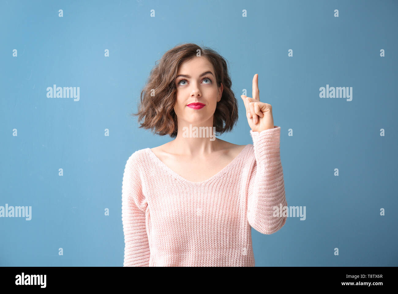 Portrait of beautiful woman with raised index finger on color ...