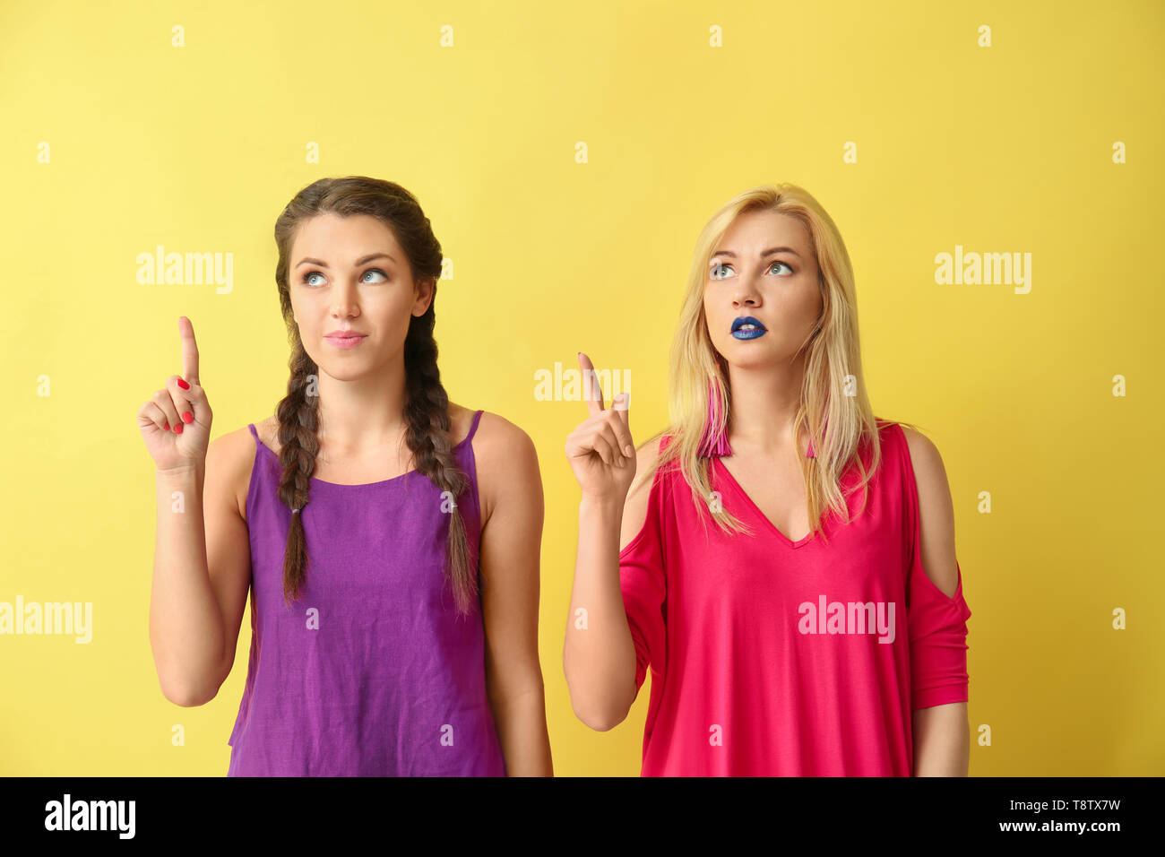 Portrait of beautiful women with raised index fingers on color ...