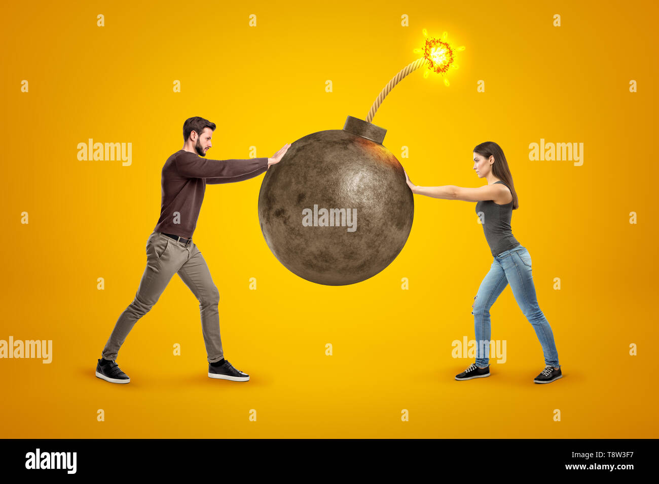 Young man and woman in casual clothes holding big ball bomb with fuse ...