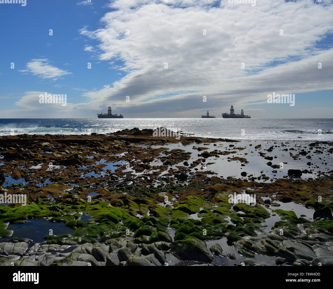 Coast landscape at low tide, cloudy sky and oil platforms in the ...
