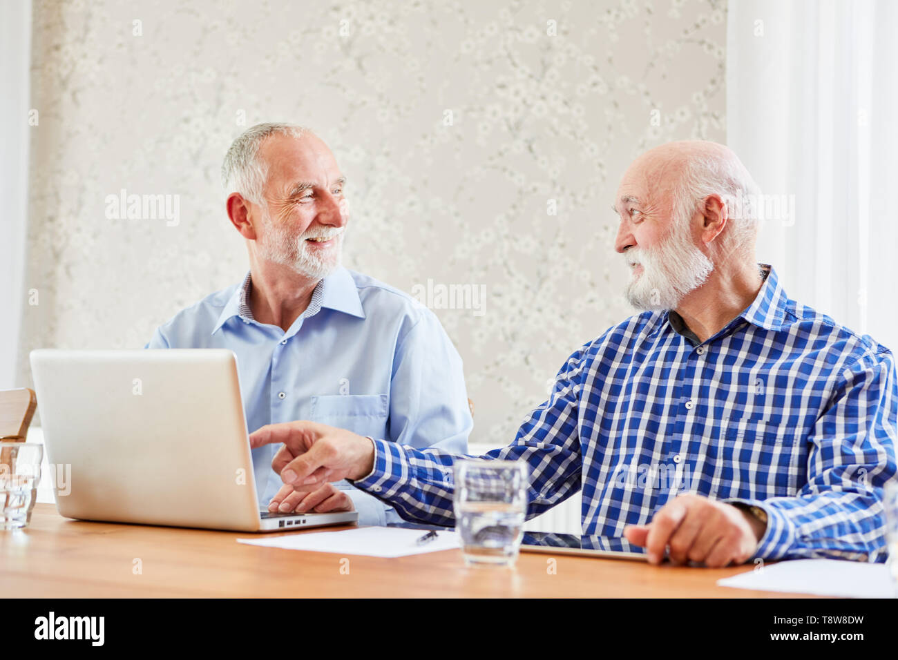 Two seniors at the laptop computer are having fun with modern ...