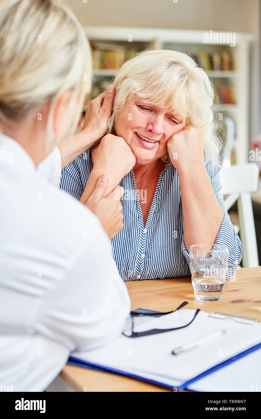 Sensitive doctor consoles crying old patient in her consultation Stock ...