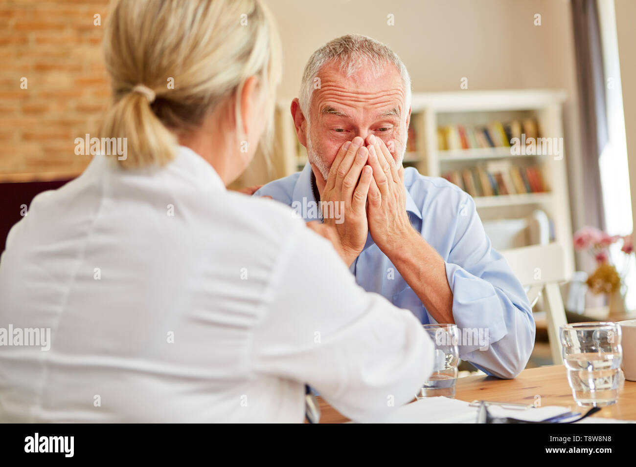 Weeping senior man as a patient with grief and a doctor on home visit ...