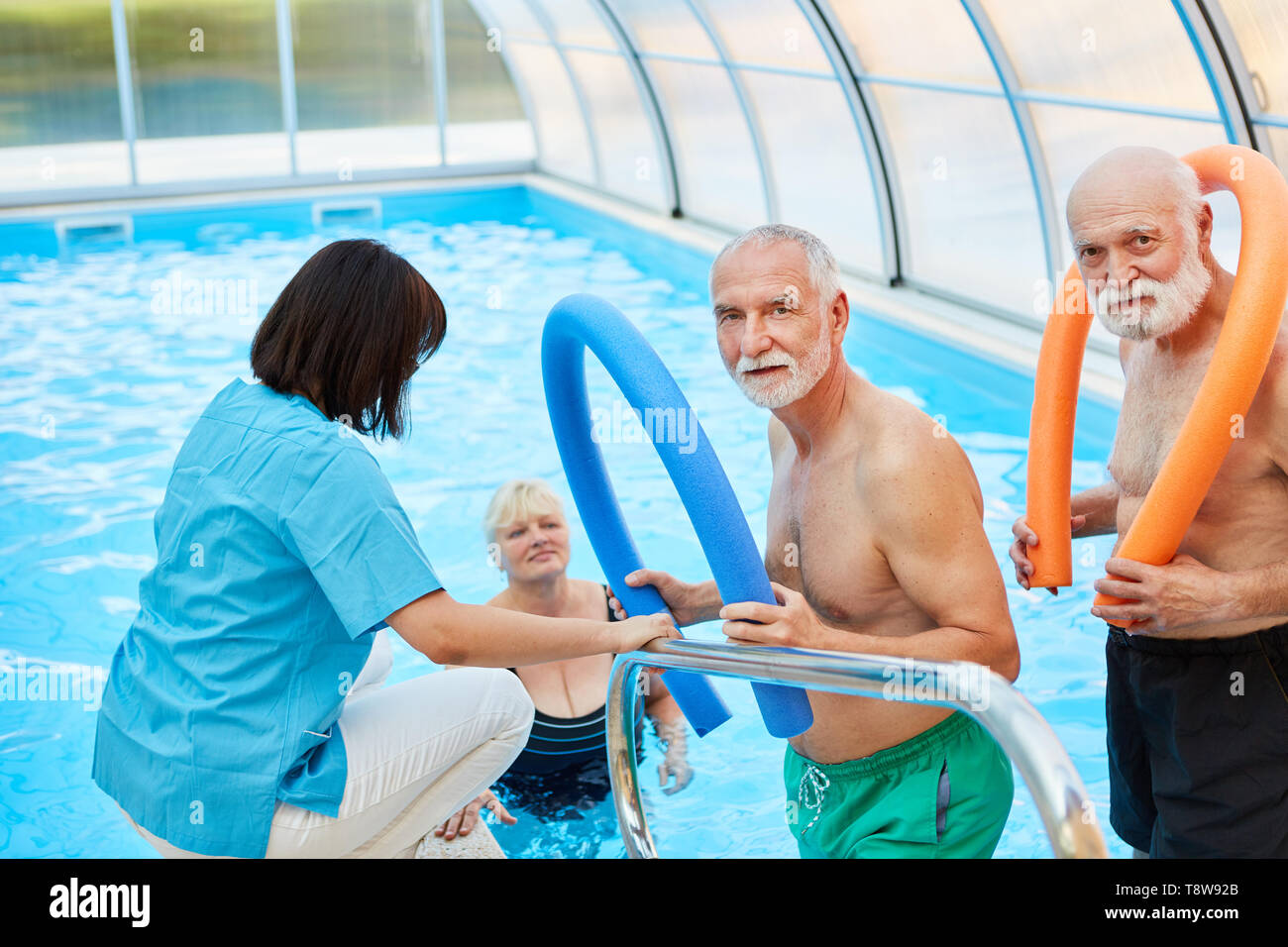 Group of seniors and therapist in swimming pool before water aerobics ...