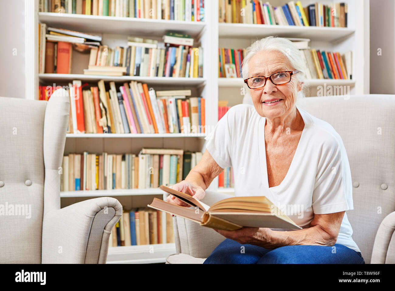 Curious senior citizen in the library reads a book for knowledge and ...